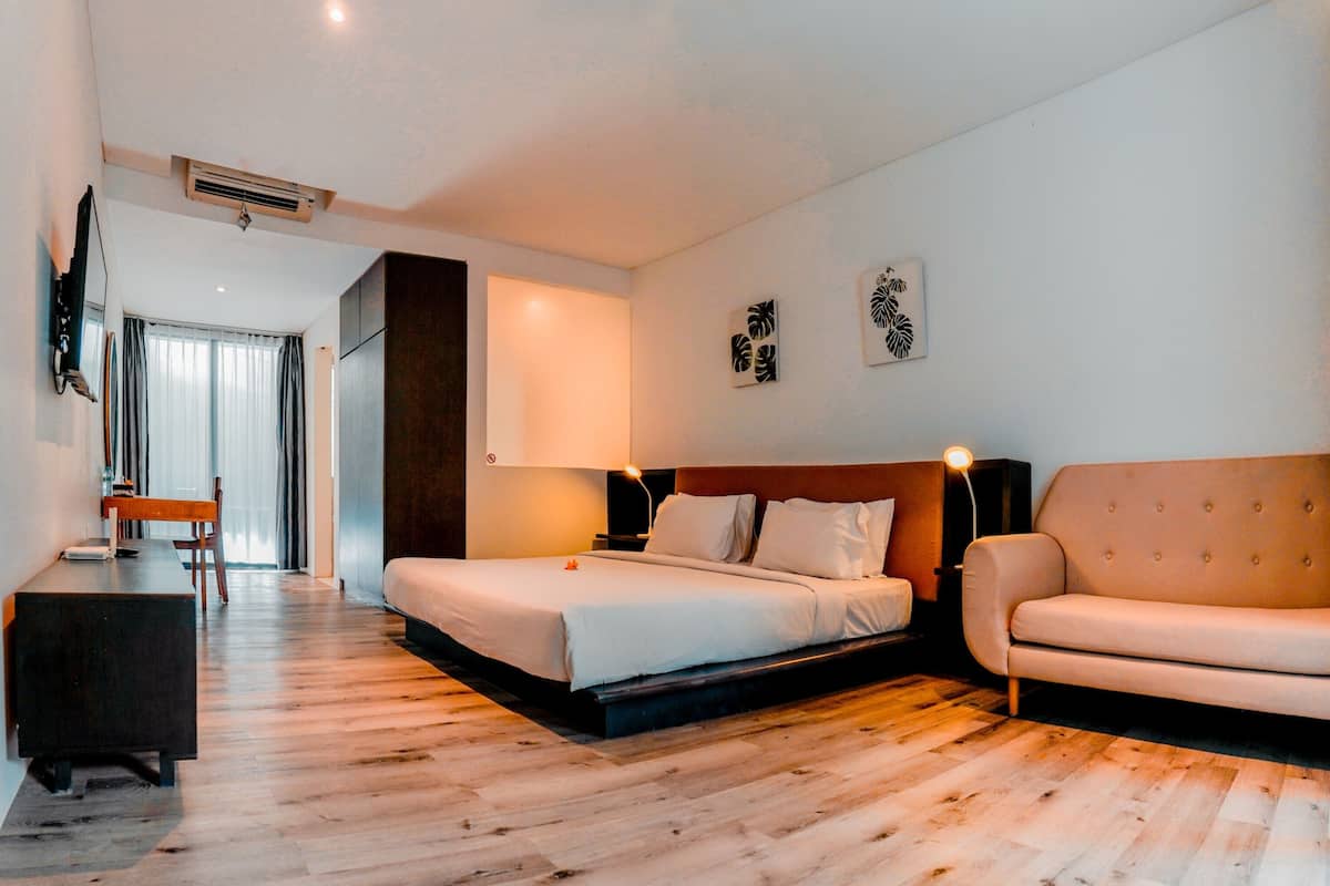 Quarto de hotel com cama, sofá, escrivaninha e uma cadeira.