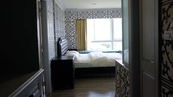 Quarto com cama, mesa de cabeceira e janela com cortinas.