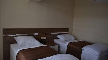 Quarto de hotel com duas camas de solteiro, cabeceira de madeira, mesa de cabeceira e uma pequena mesa.