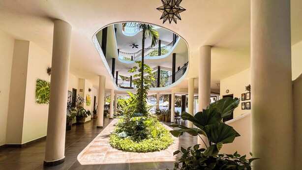 Amplo espaço interno com um átrio central, vários níveis e diversas plantas em vasos.