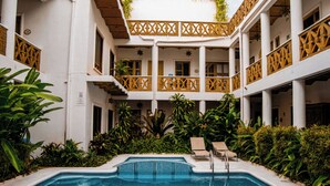 Uma área de piscina com borda em azulejo, cercada por vegetação exuberante e um cercado de madeira.