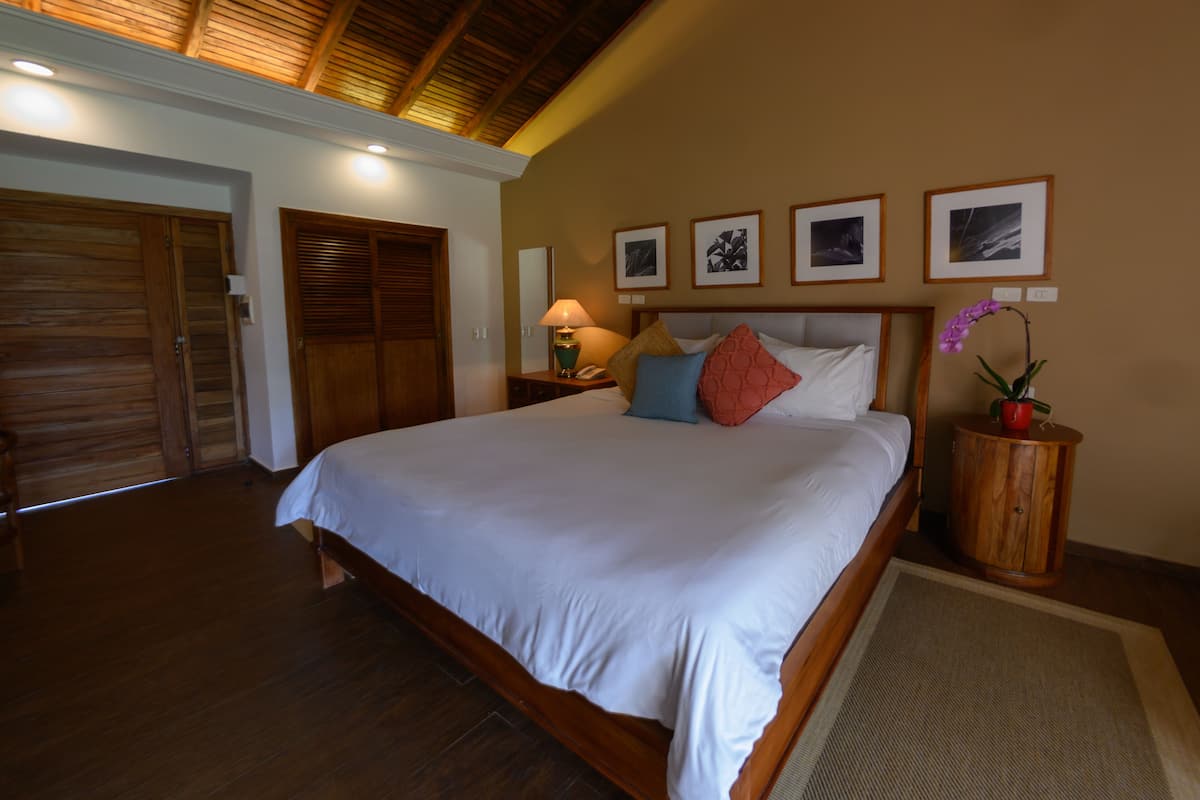 Um quarto espaçoso com uma cama grande, guarda-roupa de madeira e teto com vigas de madeira.