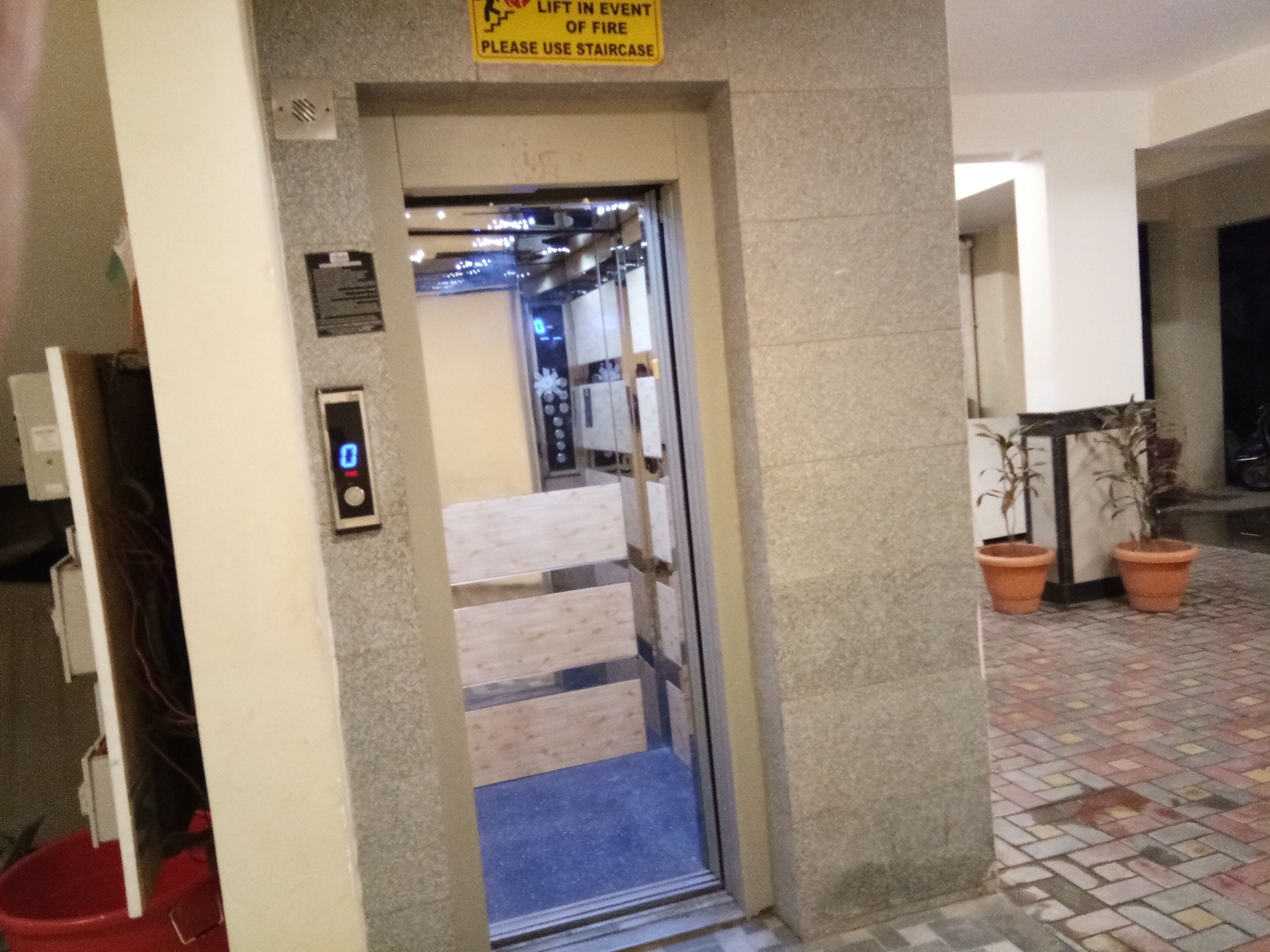 Um elevador com uma placa indicando o uso das escadas em caso de incêndio.
