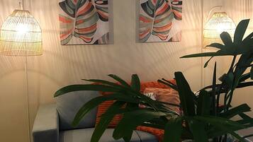 Uma sala de estar moderna com um sofá, duas pinturas abstratas e uma planta grande.