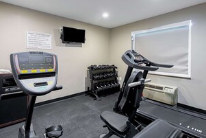 Centro de ginástica com equipamentos de cardio, halteres e esteira.