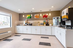 Cozinha moderna com armários brancos, cafeteira e janela com vista para o exterior.