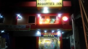 Pousada Grand Roberto com um letreiro de neon, entrada visível e uma placa para artigos de casa.