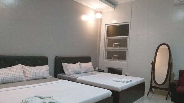 Quarto de hotel com duas camas, um espelho, uma cadeira vermelha e uma estante embutida.