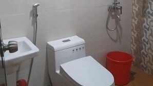 Casa de banho com sanita, lavatório e chuveiro.