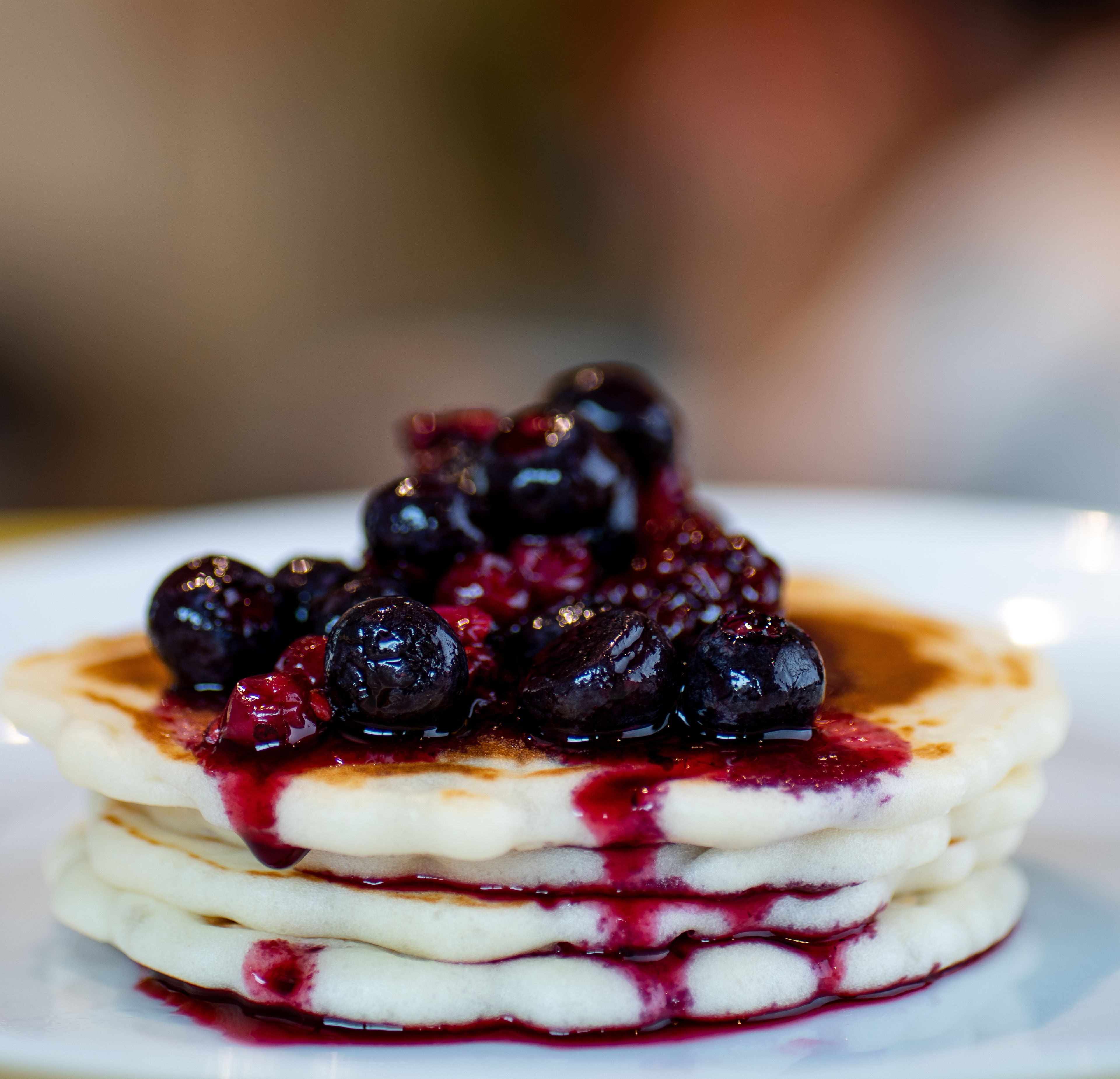 Uma pilha de panquecas com blueberries e calda.