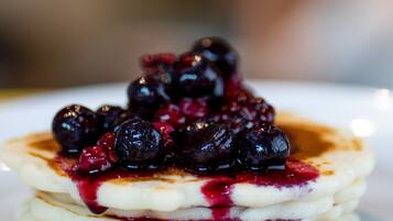 Uma pilha de panquecas com blueberries e calda.