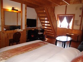 Um quarto aconchegante com cama, escrivaninha, cadeira, televisão e escada.