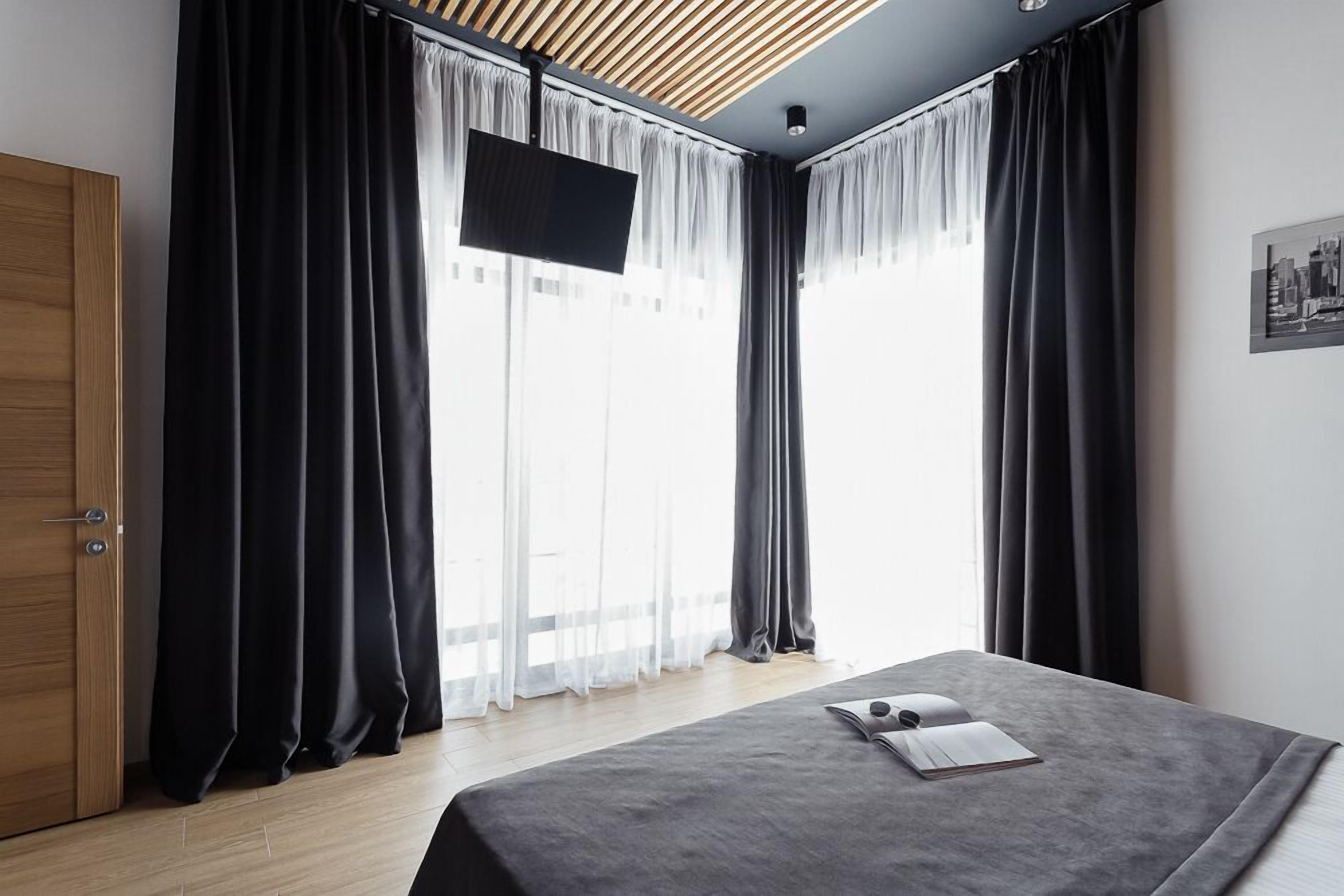 Quarto de hotel moderno com cama grande, televisão de tela plana e vista para a cidade.