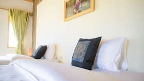 Quarto de hotel com duas camas, um quadro na parede e uma janela com cortinas verdes.