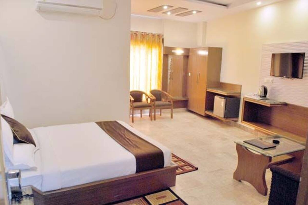 Quarto de hotel com cama, escrivaninha, cadeira e guarda-roupa.