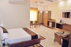 Quarto de hotel com cama, escrivaninha, cadeira e guarda-roupa.