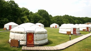 Yurts dispostas em fileiras, com um caminho de madeira serpenteando entre elas.