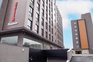 Um edifício moderno com uma placa de destaque para 'Residences' e uma fachada visível para 'Slaviero Slim'.