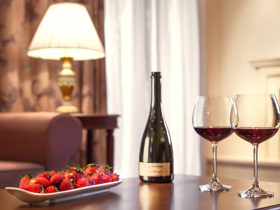 Uma mesa com uma garrafa de vinho, duas taças de vinho e um prato de morangos.