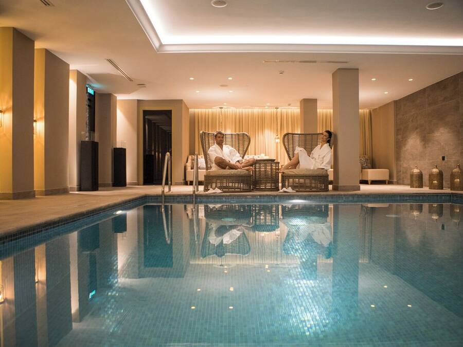 Piscina com espreguiçadeiras e área de estar com cortinas.