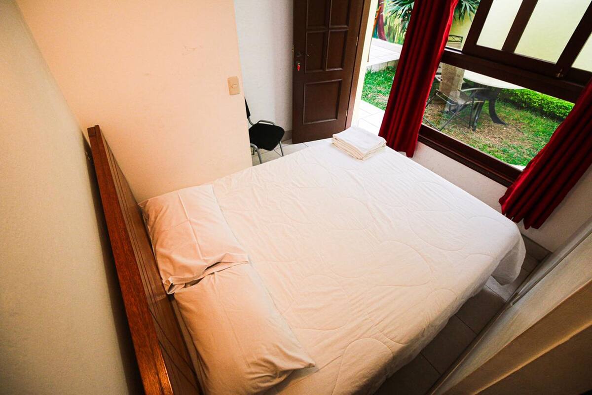 Uma cama bem arrumada com cabeceira de madeira em um quarto com janela e porta.