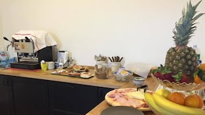 Uma bancada de cozinha com diversos alimentos, incluindo abacaxi, bananas e uma fruteira.