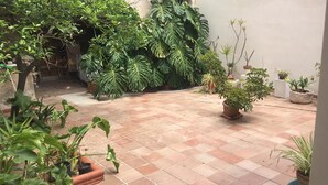 Um pátio com plantas em vasos e piso de azulejos.