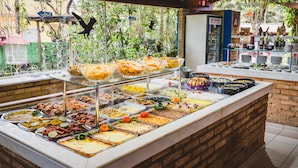 Buffet com diversas opções de comida e vista para o verde lá fora.