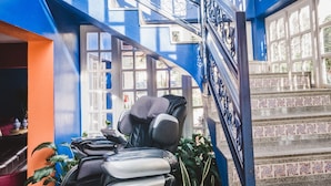 Uma cadeira de massagem num quarto bem iluminado, com uma parede azul e uma escadaria revestida a azulejos.