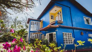 Um edifício de dois andares com fachada azul, molduras de janela brancas e telhado de telhas vermelhas.