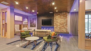Uma sala de estar moderna com uma parede de destaque em pedra, uma TV de tela plana e uma variedade de opções de assento, incluindo um sofá e poltronas.