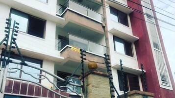 Um edifício com vários andares, varandas, um aviso de venda e uma placa de visitante à direita.