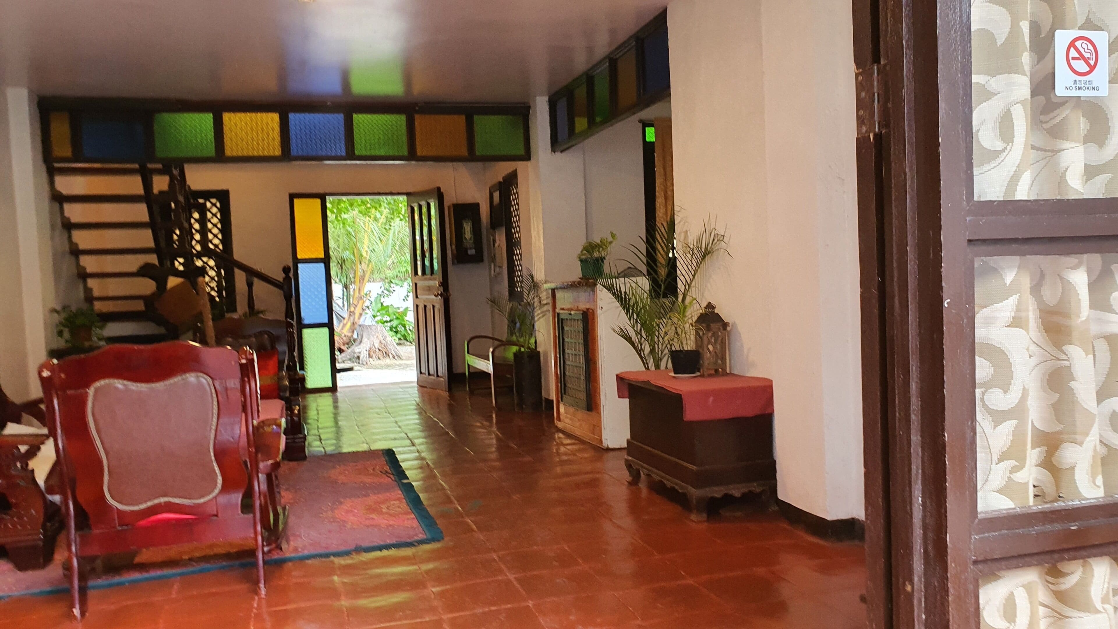 Um corredor com escadas, uma cadeira vermelha, um banco de madeira e um vaso de planta.
