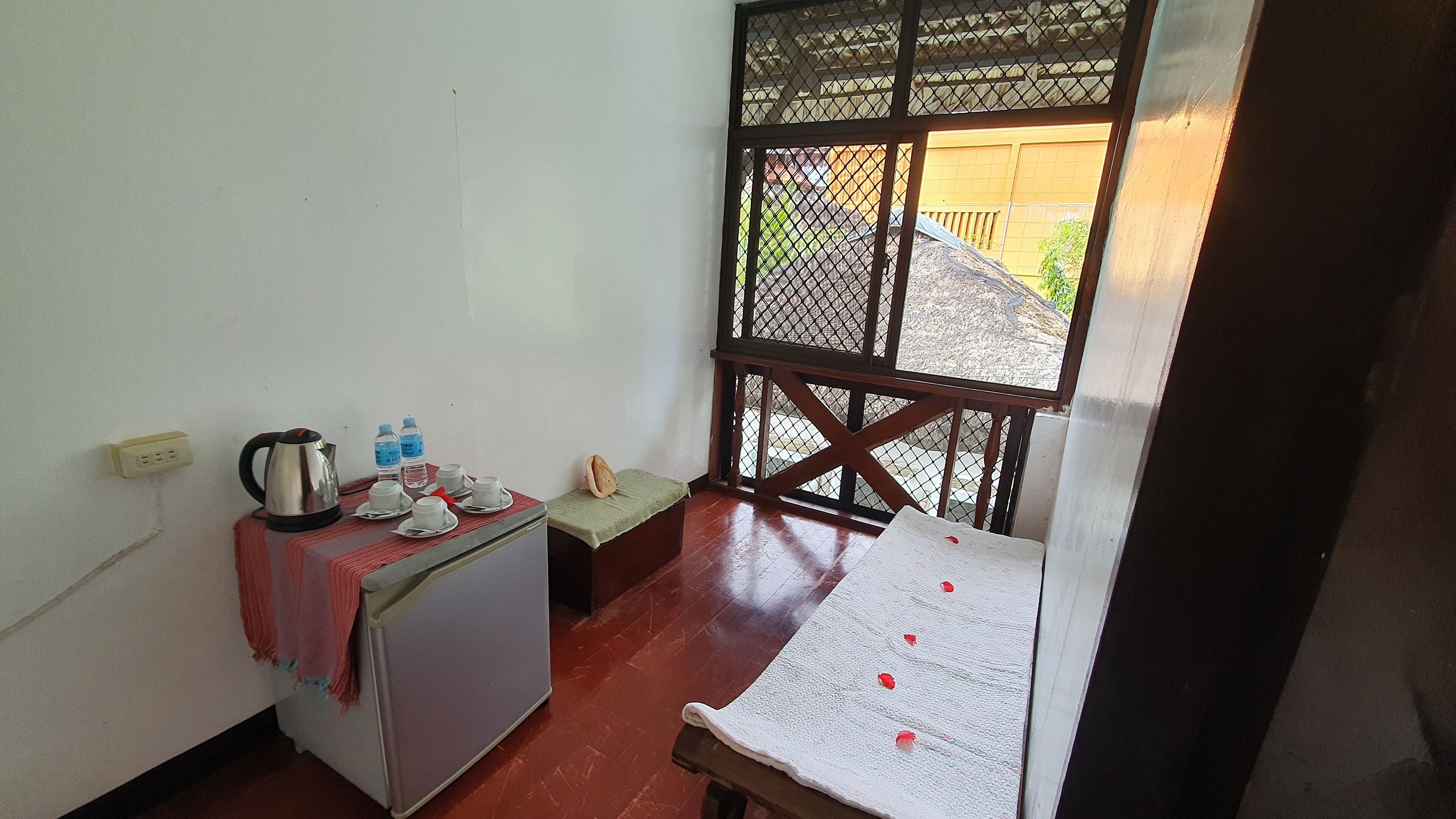Uma pequena cozinha compacta com geladeira, chaleira e garrafas de água sobre uma mesa.