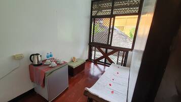 Uma pequena cozinha compacta com geladeira, chaleira e garrafas de água sobre uma mesa.