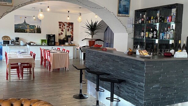 Uma cozinha moderna com área de bar, banquetas vermelhas e espaço de refeições com cadeiras vermelhas.