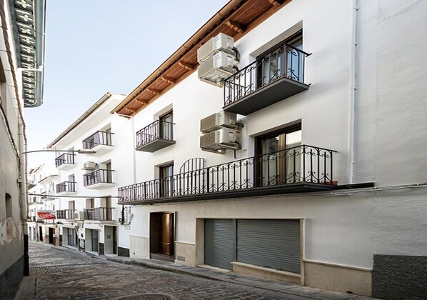 Uma rua estreita com edifícios altos, sacadas e aparelhos de ar condicionado.