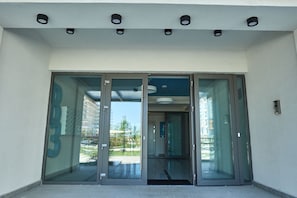 Entrada de um edifício moderno com portas de vidro e vista desobstruída para o exterior.