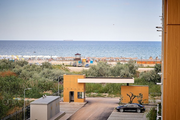 Vista costeira com praia, torre de salva-vidas e estacionamento.