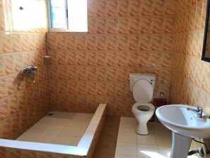 Casa de banho com chuveiro, sanita e lavatório.