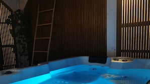 Uma banheira de hidromassagem com luz azul, rodeada por painéis de madeira e uma escada.