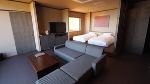 Quarto de hotel moderno com sofá, televisão, máquina de café e guarda-roupa.