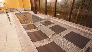 Piscina com várias pistas de natação, corrimãos de metal e piso revestido de azulejos.