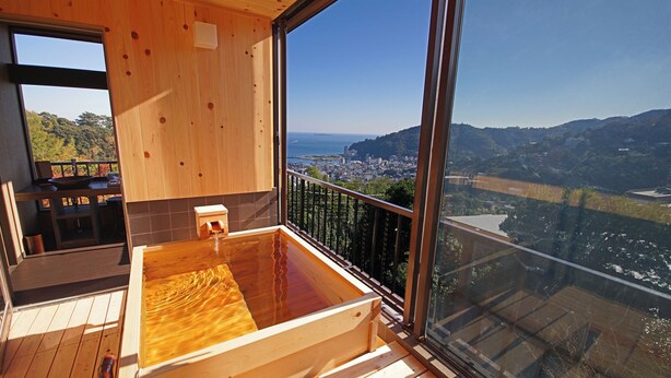 Uma cabana de madeira com uma banheira grande, área de jantar e varanda com vista para a cidade.