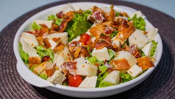 Uma salada com alface, tomates, croutons e bacon.