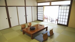 Um quarto japonês tradicional com tatames, uma mesa de madeira baixa e portas deslizantes.