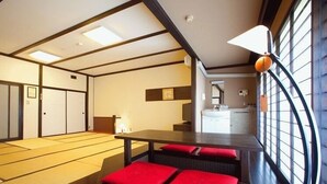 Um quarto japonês tradicional com piso de tatame, uma mesa baixa e almofadas vermelhas.