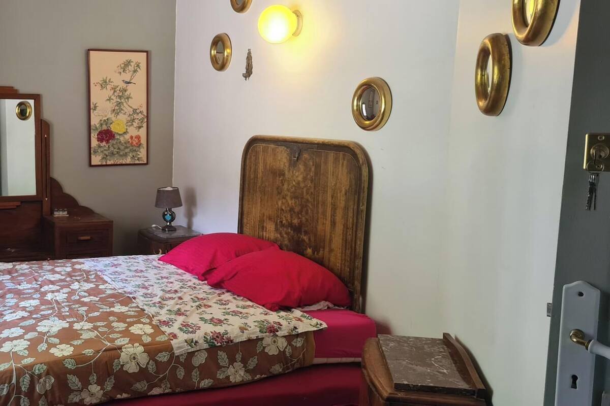 Quarto com cama, penteadeira, espelho e luminárias na parede.
