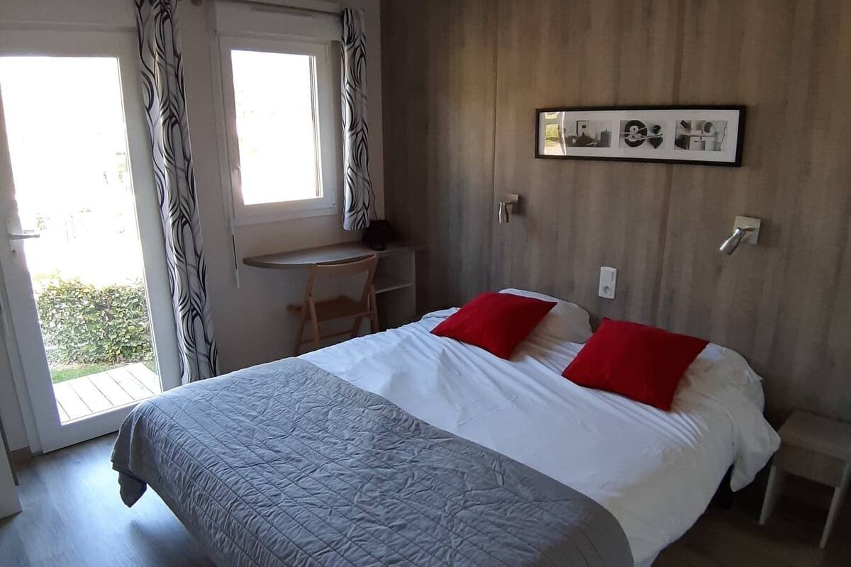 Quarto com cama, escrivaninha e janela.