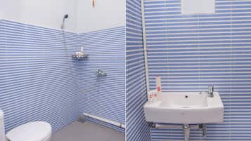 Casa de banho com azulejos azul e branco listrados, uma pia branca e uma sanita.